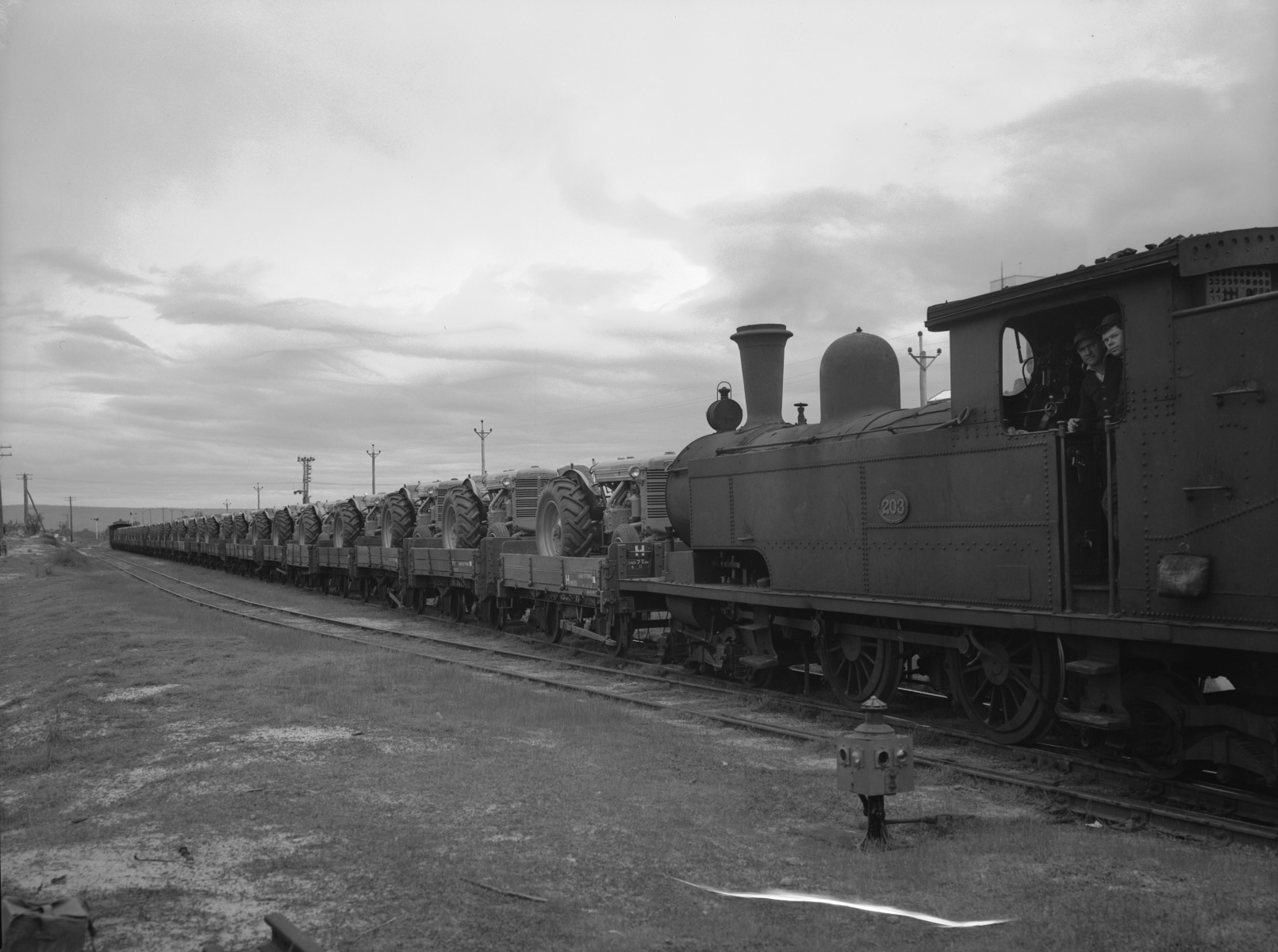 Chamberlain tractor on railway wagons being pushed by steam locomotive ...