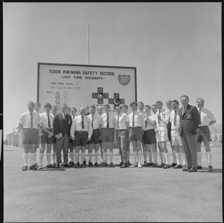 Group of VFL umpires in front of a BP Australia safety sign, October ...